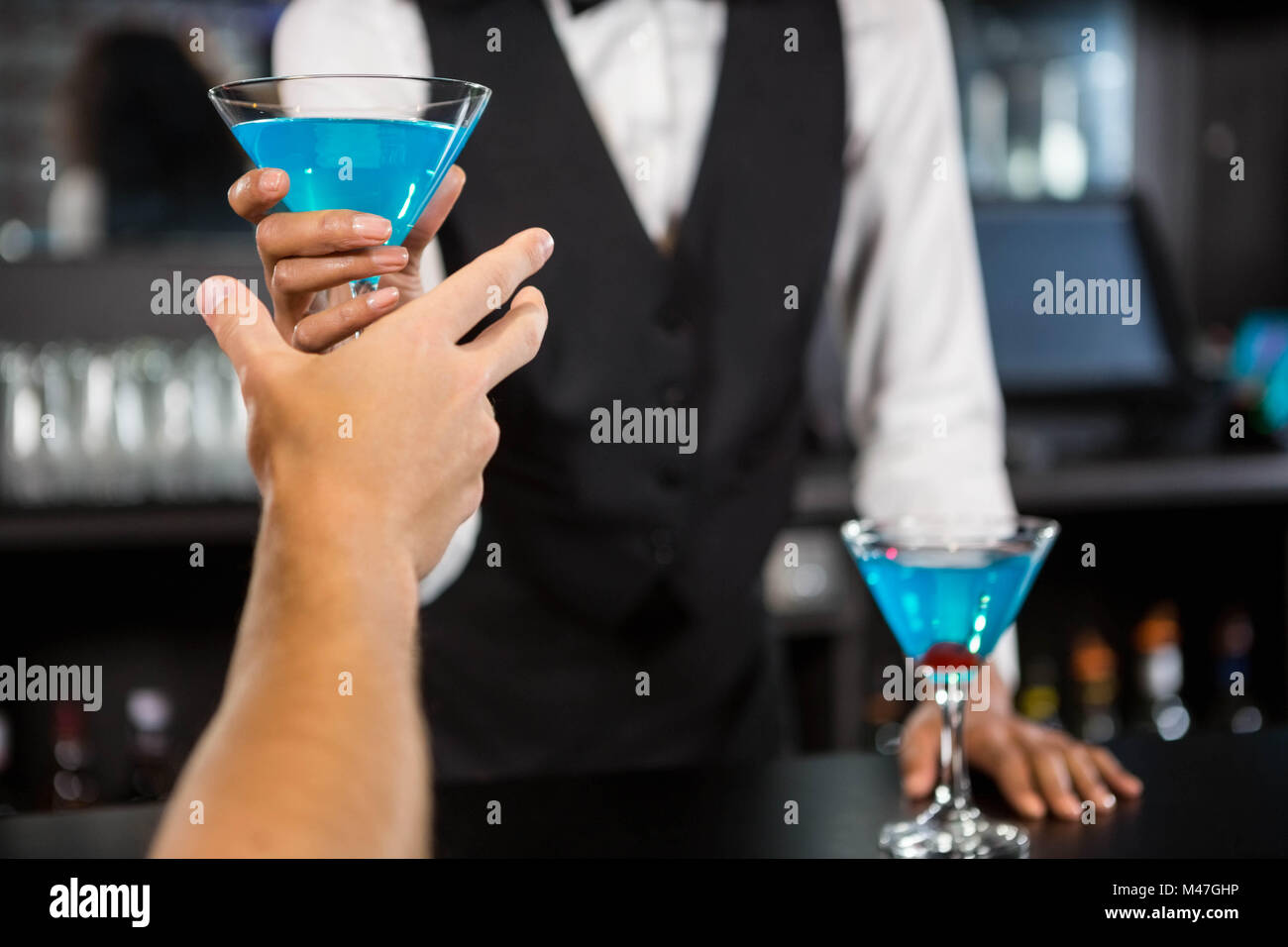 Bartender serving blue cocktail at bar counter Stock Photo - Alamy