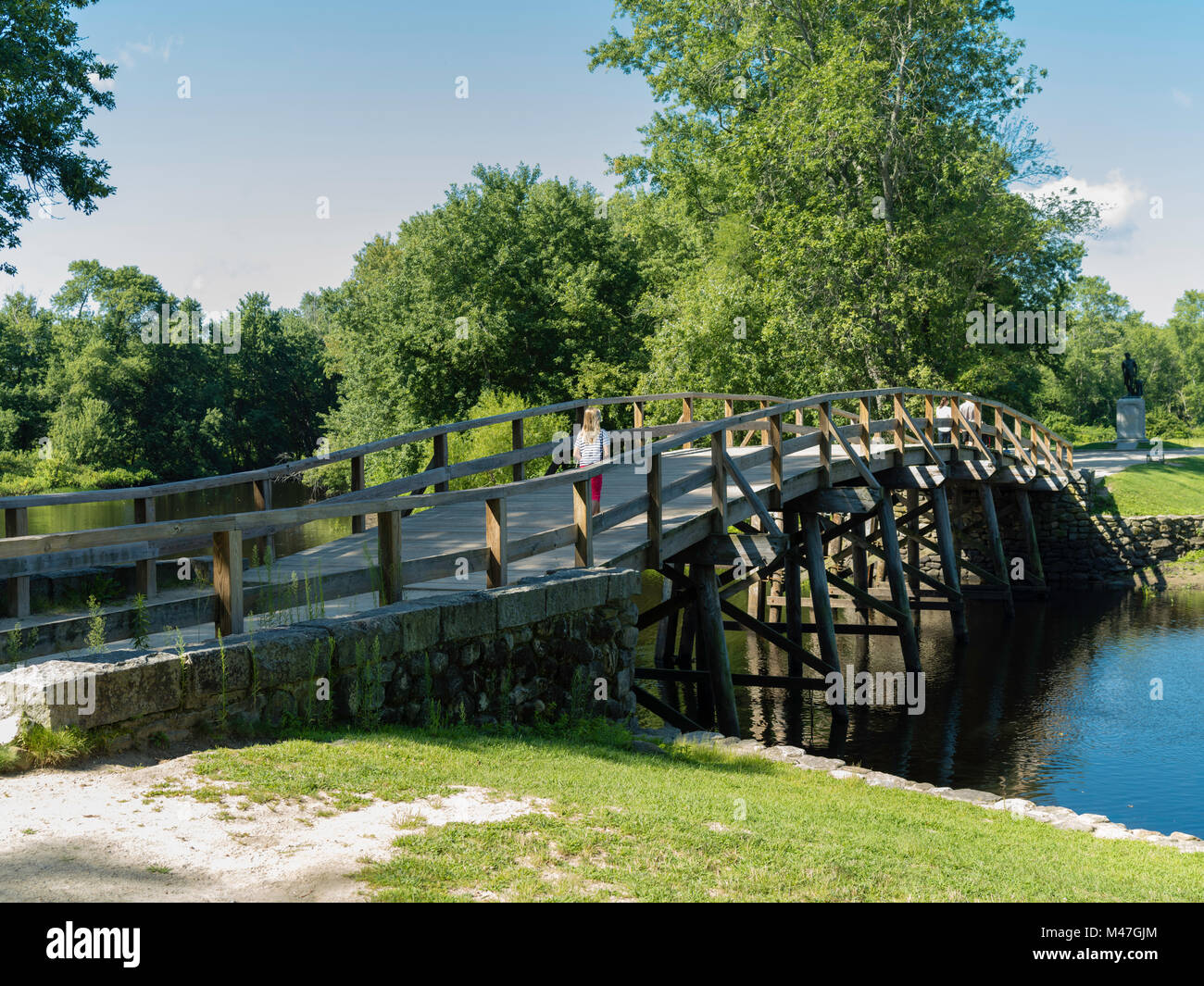 People walk across the Old North Bridge over the Concord River while exploring Minute Man ...