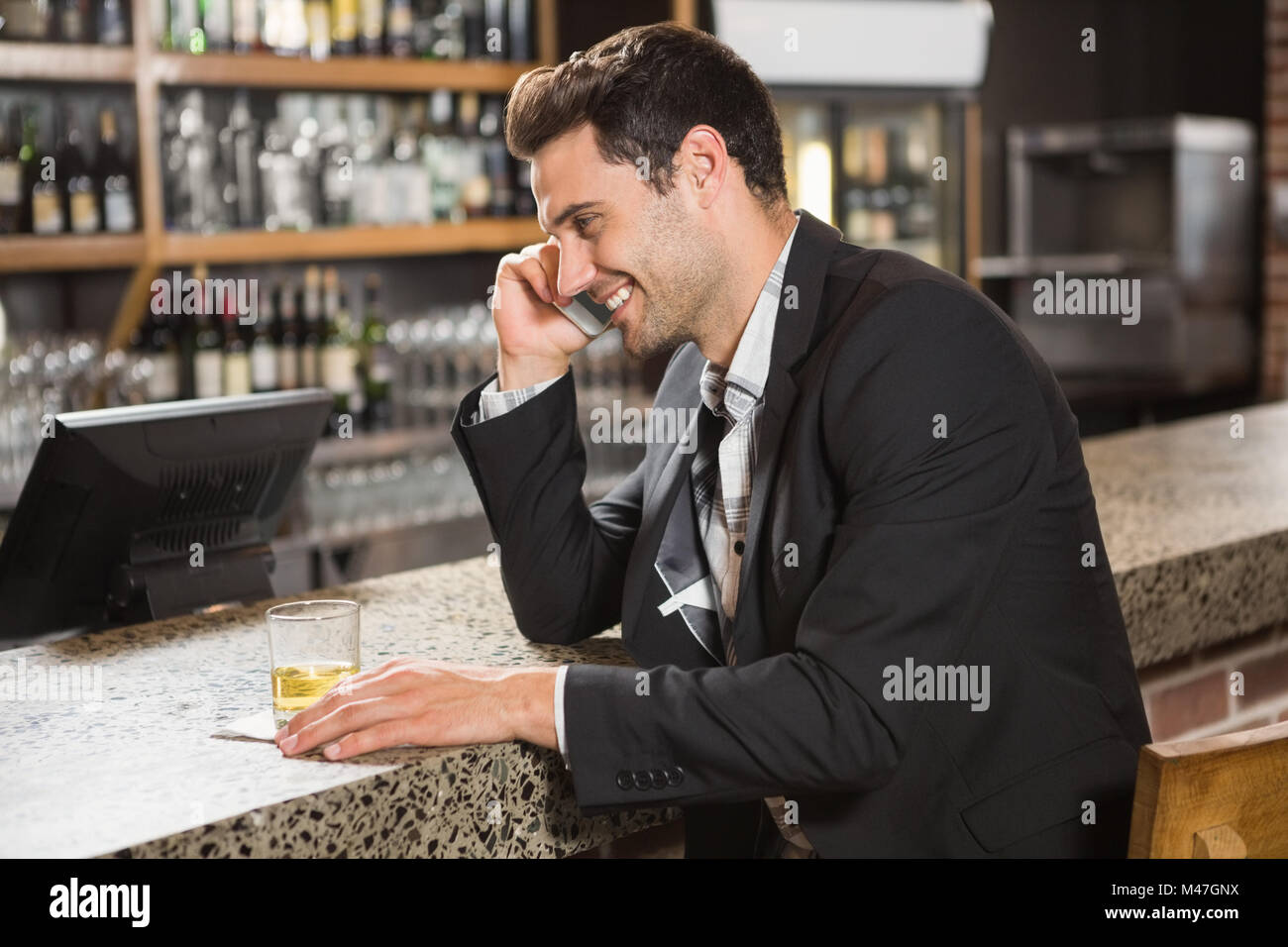 Handsome man having a whiskey and a phone call Stock Photo - Alamy