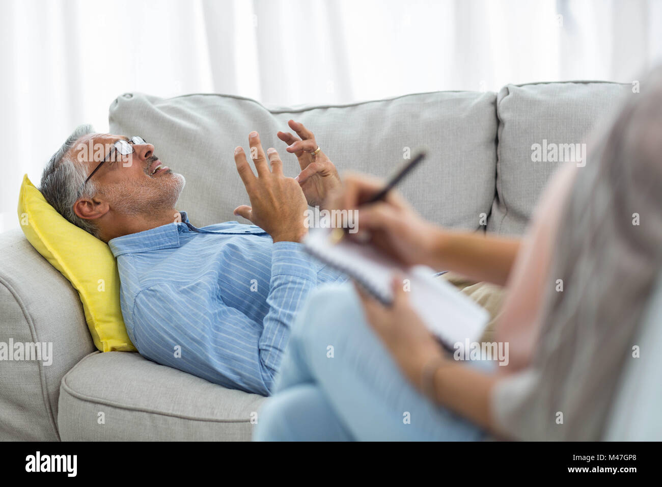 Female doctor writing on notepad while consulting a man Stock Photo - Alamy