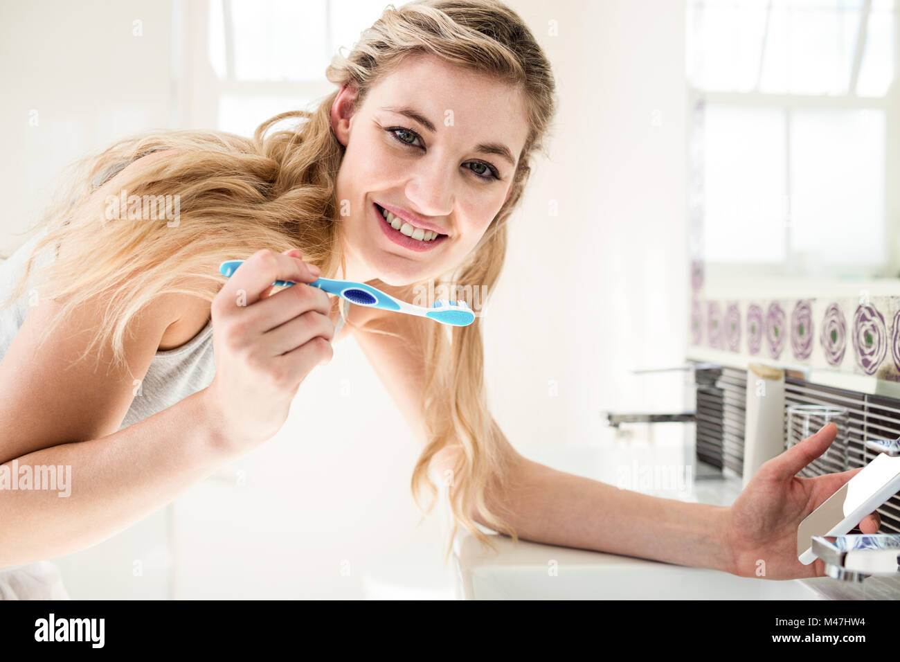 Portrait of happy woman brushing teeth at sink Stock Photo - Alamy