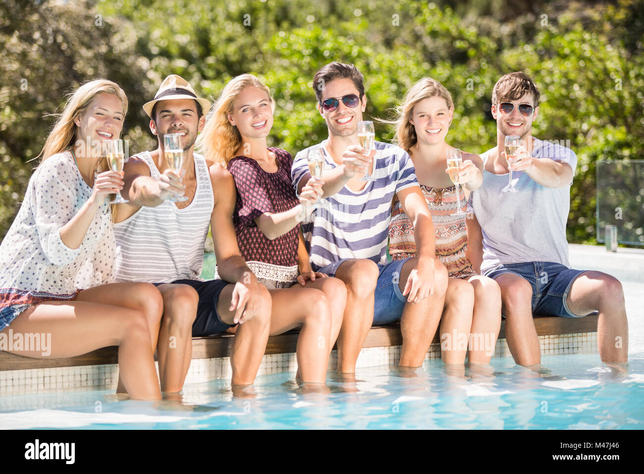Group of friends sitting at poolside with glass of champagne Stock ...