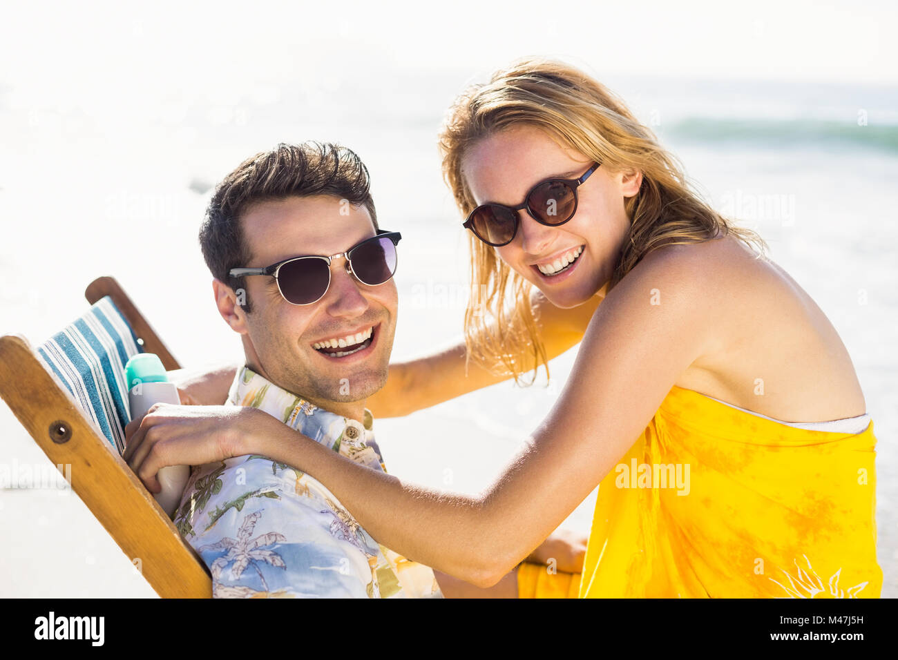 Portrait of young couple sitting on arm chair and embracing Stock Photo ...