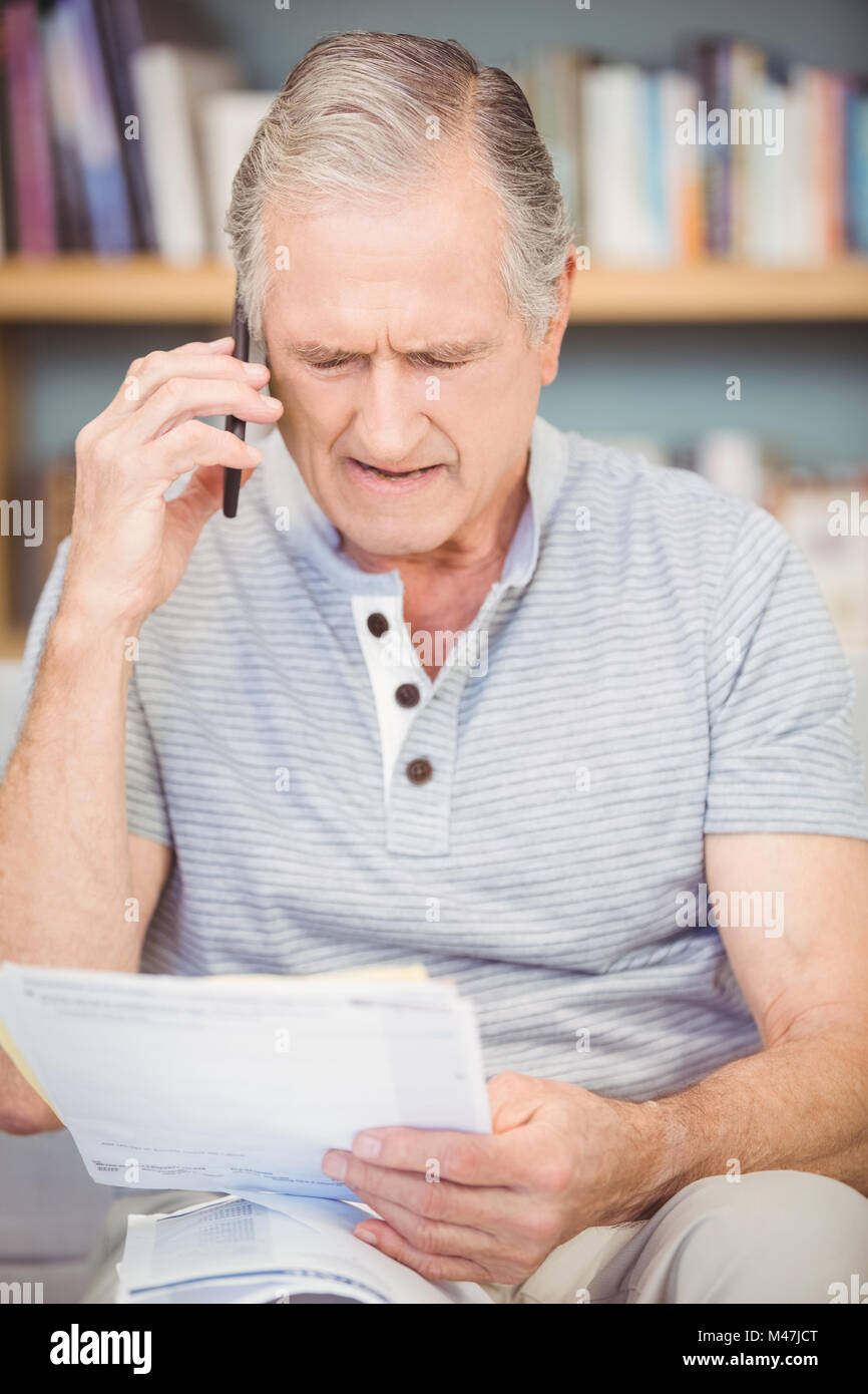Senior man talking on mobile phone while looking documents Stock Photo ...