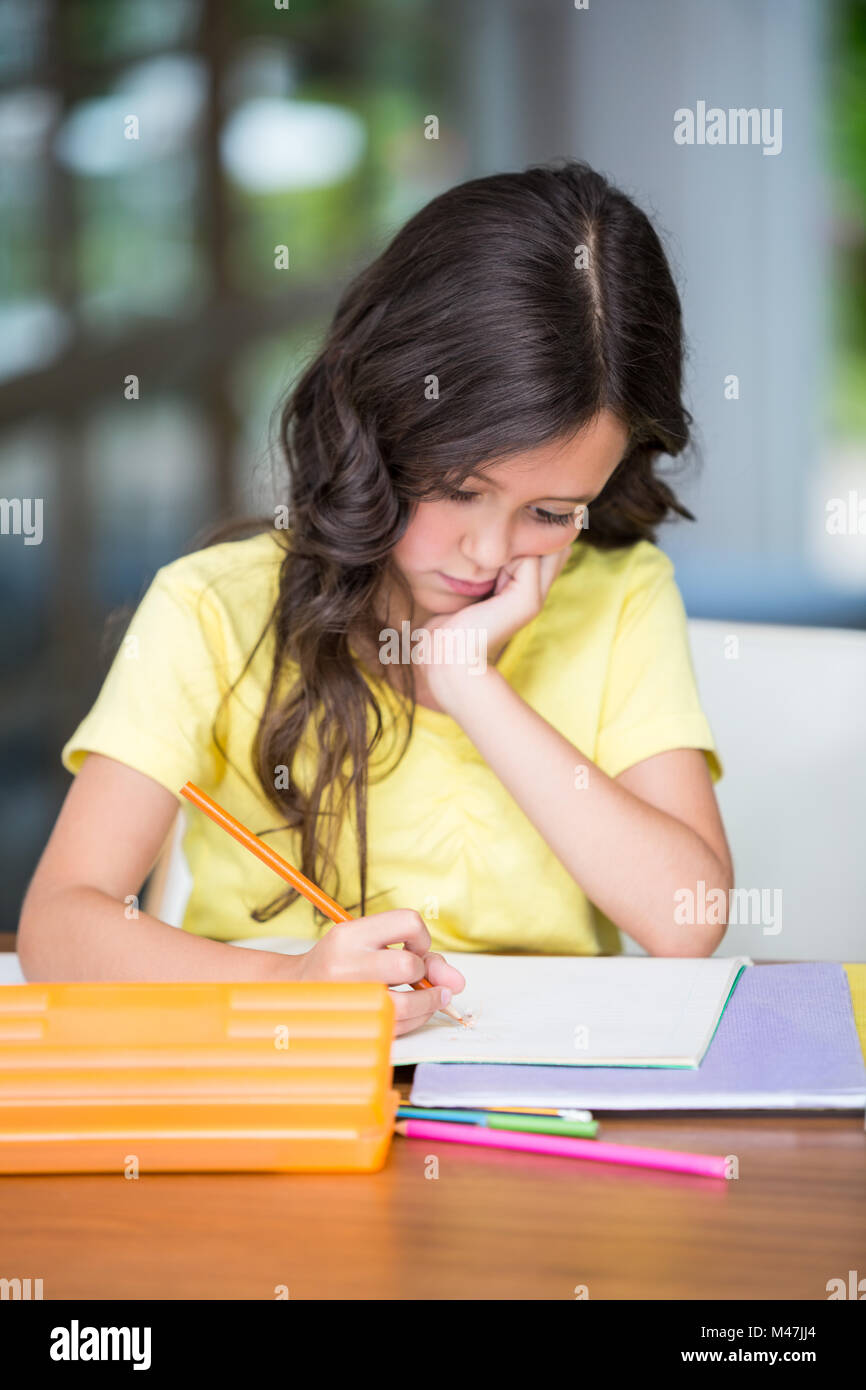 Concentrated girl studying while sitting at desk Stock Photo - Alamy