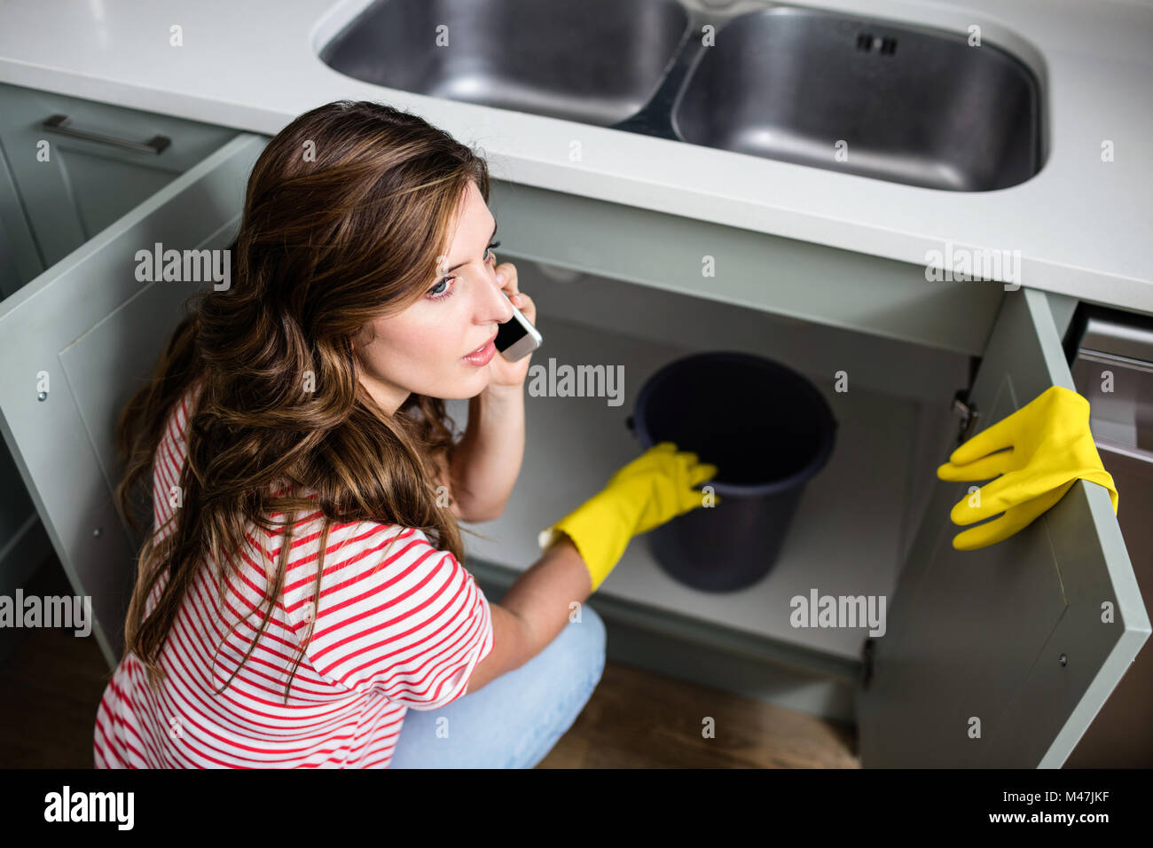 Woman talking on mobile phone while holding bucket Stock Photo - Alamy