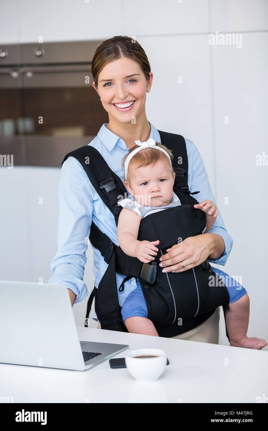 Happy woman carrying baby girl while using laptop Stock Photo - Alamy