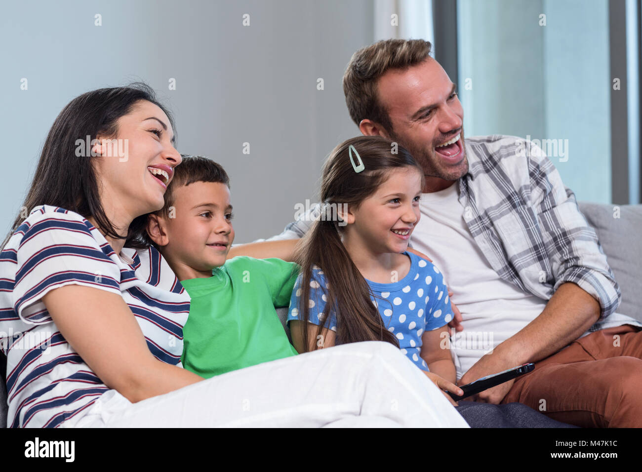 Happy young family watching television with their two children Stock ...