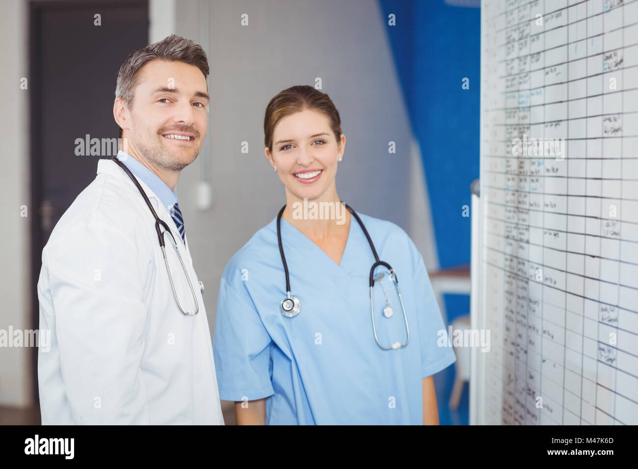 Portrait of cheerful doctors standing by chart on wall Stock Photo - Alamy