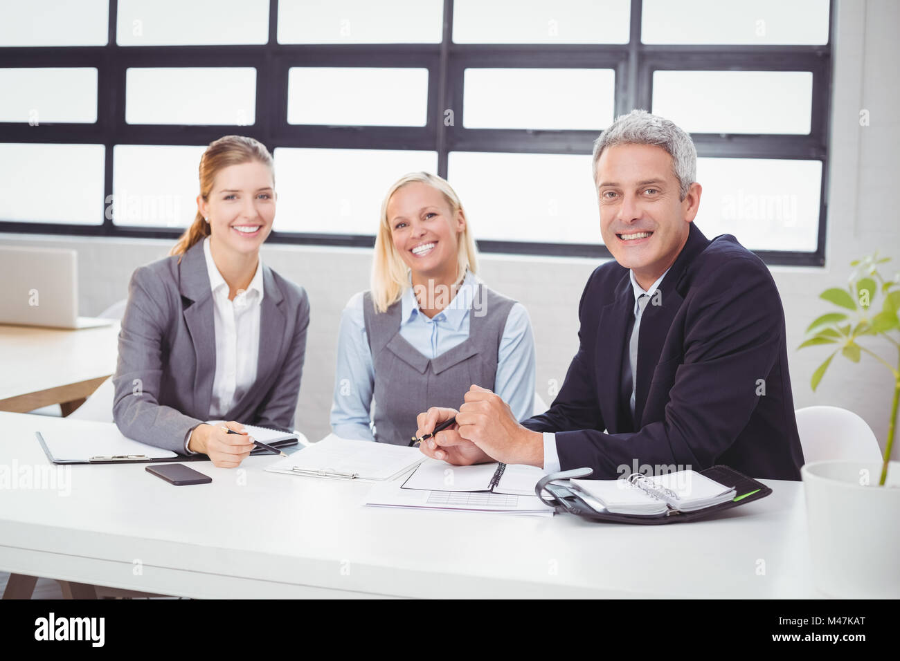 Happy business people sitting with client at desk Stock Photo - Alamy