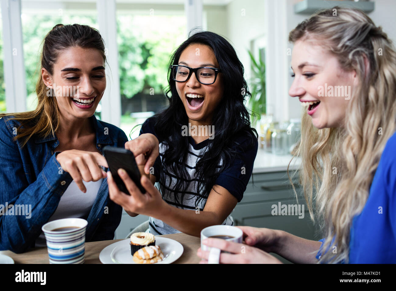 Female friends laughing while pointing on mobile phone Stock Photo - Alamy