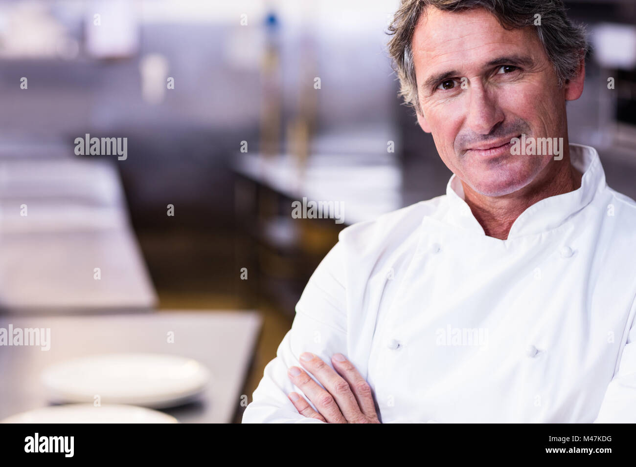 Smiling chef with hands crossed in the kitchen Stock Photo - Alamy