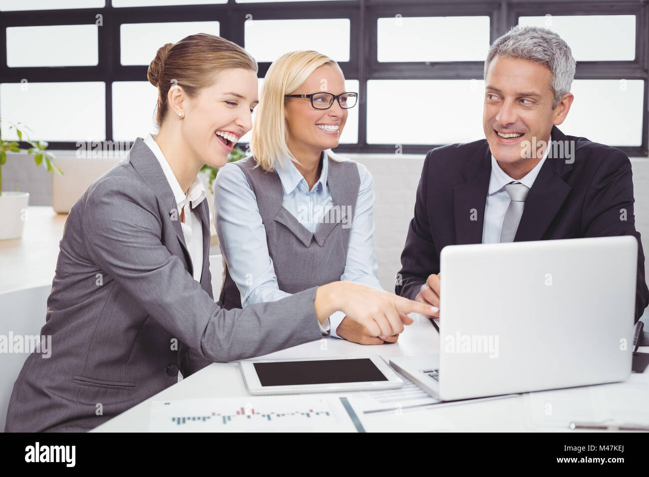 Business people smiling while discussing over laptop Stock Photo - Alamy