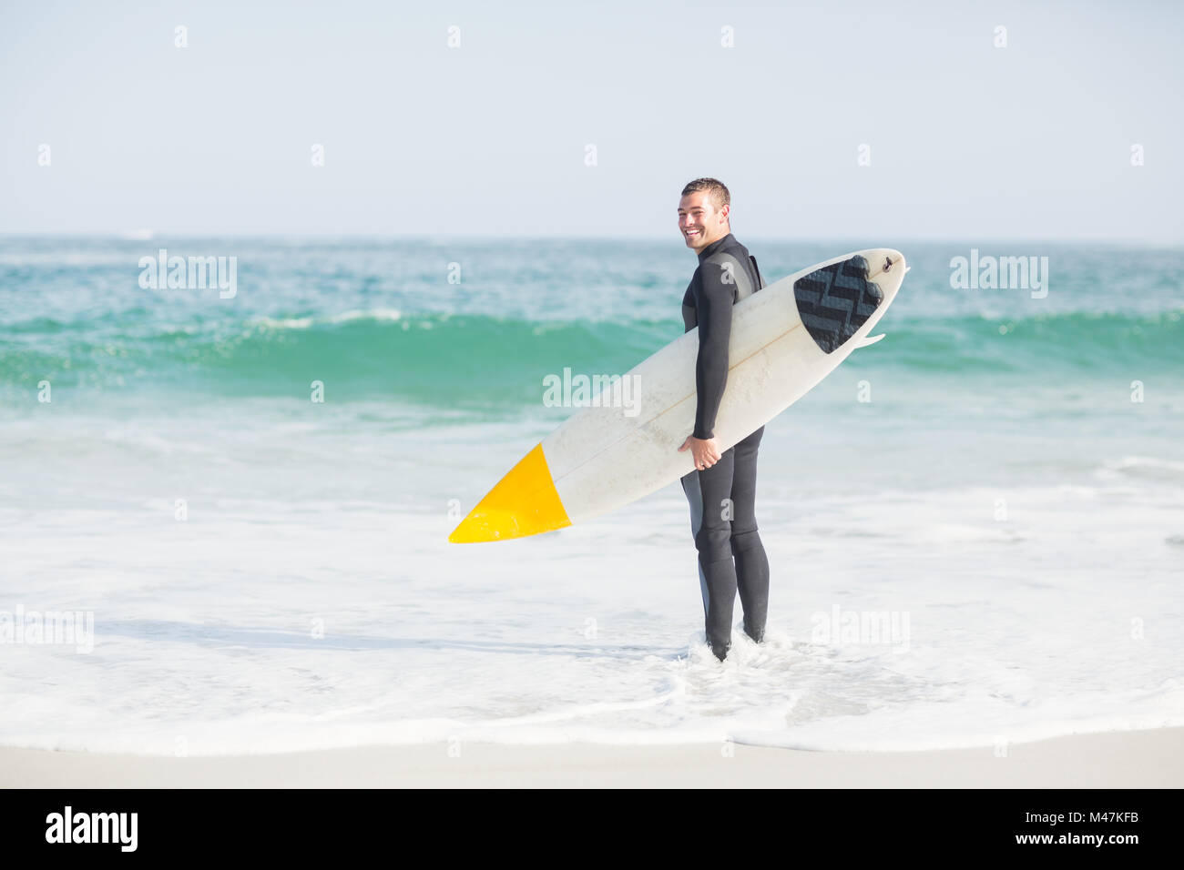Surfer standing on the beach with a surfboard Stock Photo - Alamy