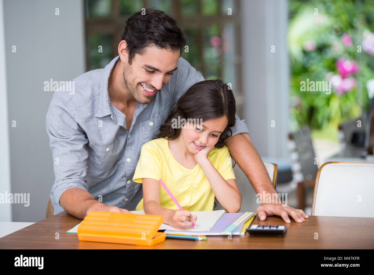 Smiling father assisting daughter with homework Stock Photo - Alamy
