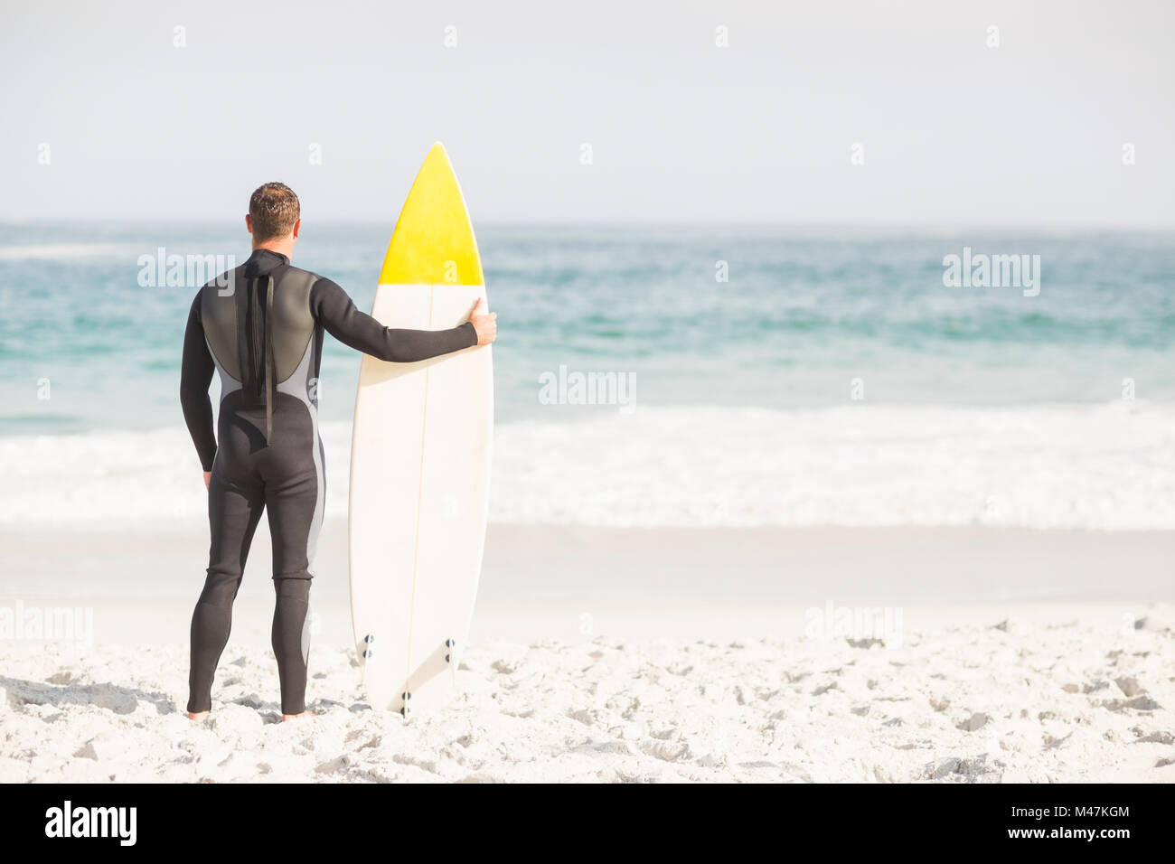 Rear view of man with surfboard standing on the beach Stock Photo - Alamy