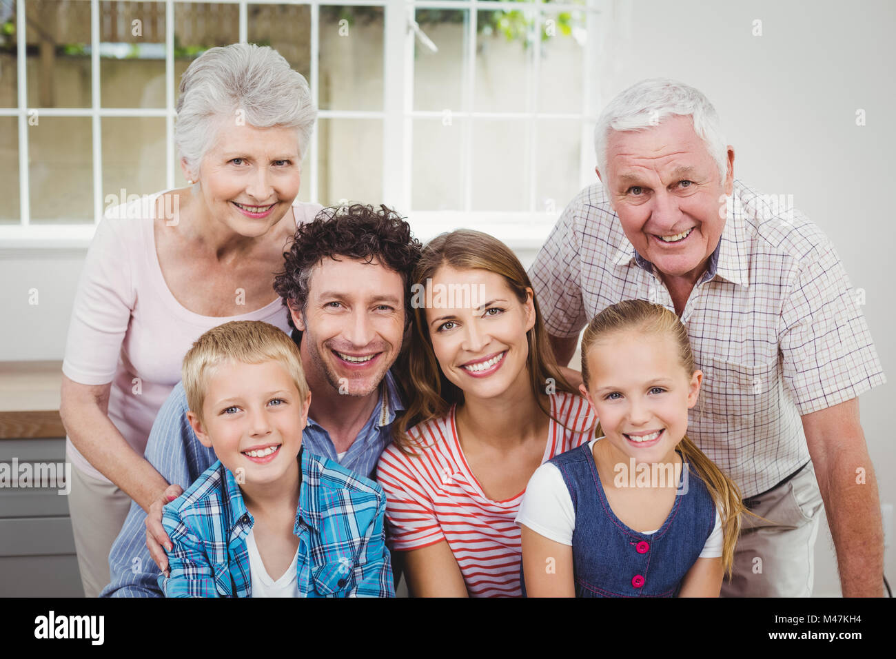 Happy multi-generation family against window at home Stock Photo - Alamy