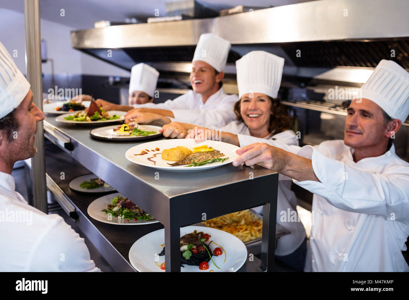Chefs handing dinner plates through order station Stock Photo - Alamy