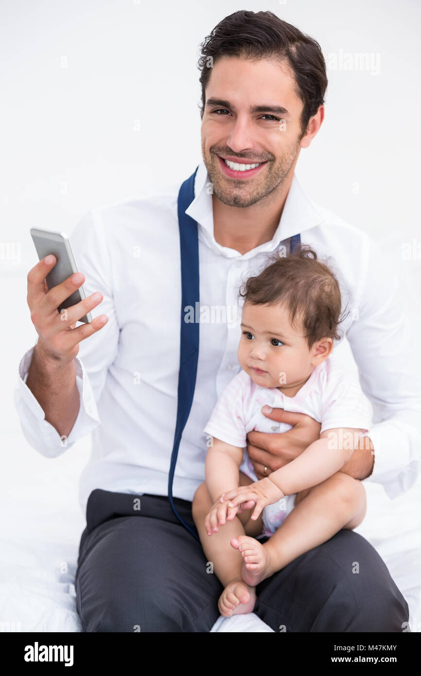 Portrait of smiling father holding mobile phone with baby Stock Photo ...