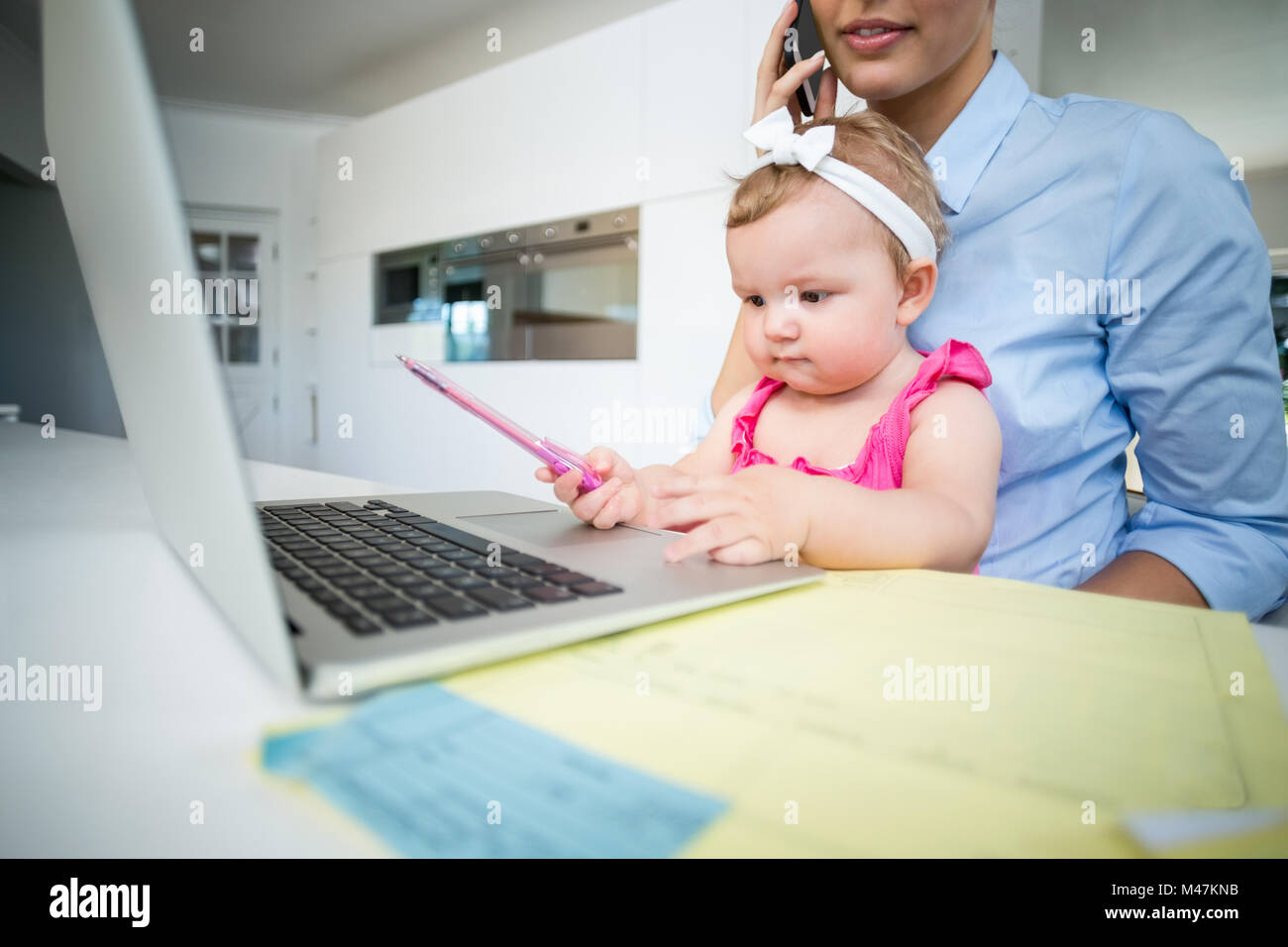 Playful baby girl sitting with mother by laptop Stock Photo - Alamy