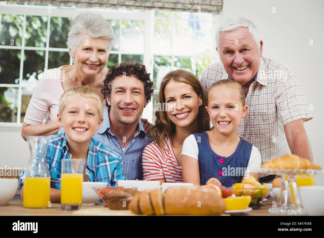 Happy multi-generation family by breakfast table Stock Photo - Alamy