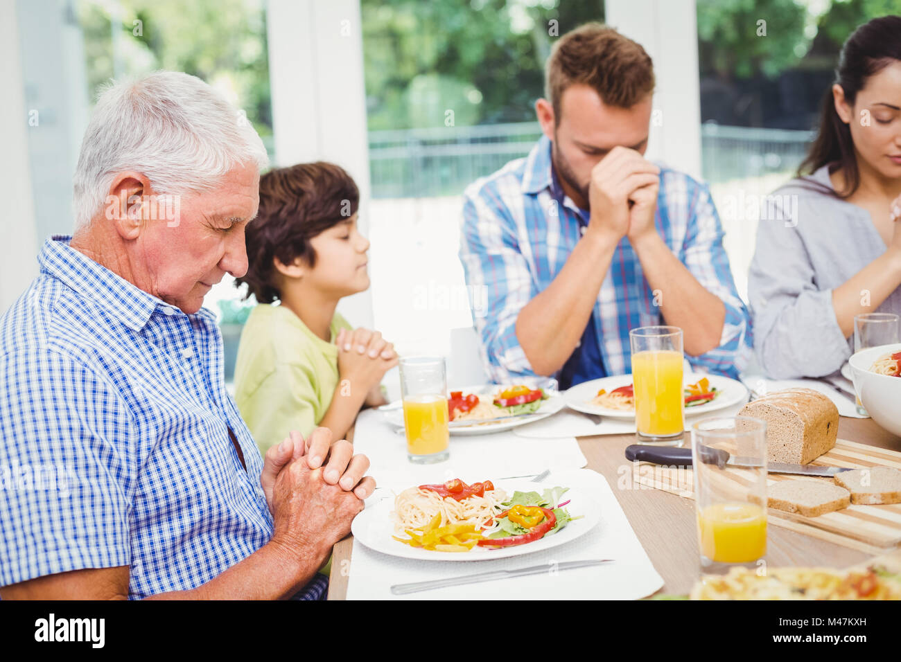 Multi generation family praying while sitting at dining table Stock ...