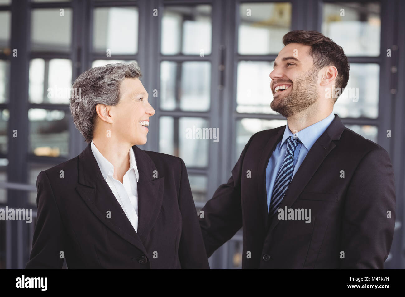 Business people laughing while standing in office Stock Photo - Alamy