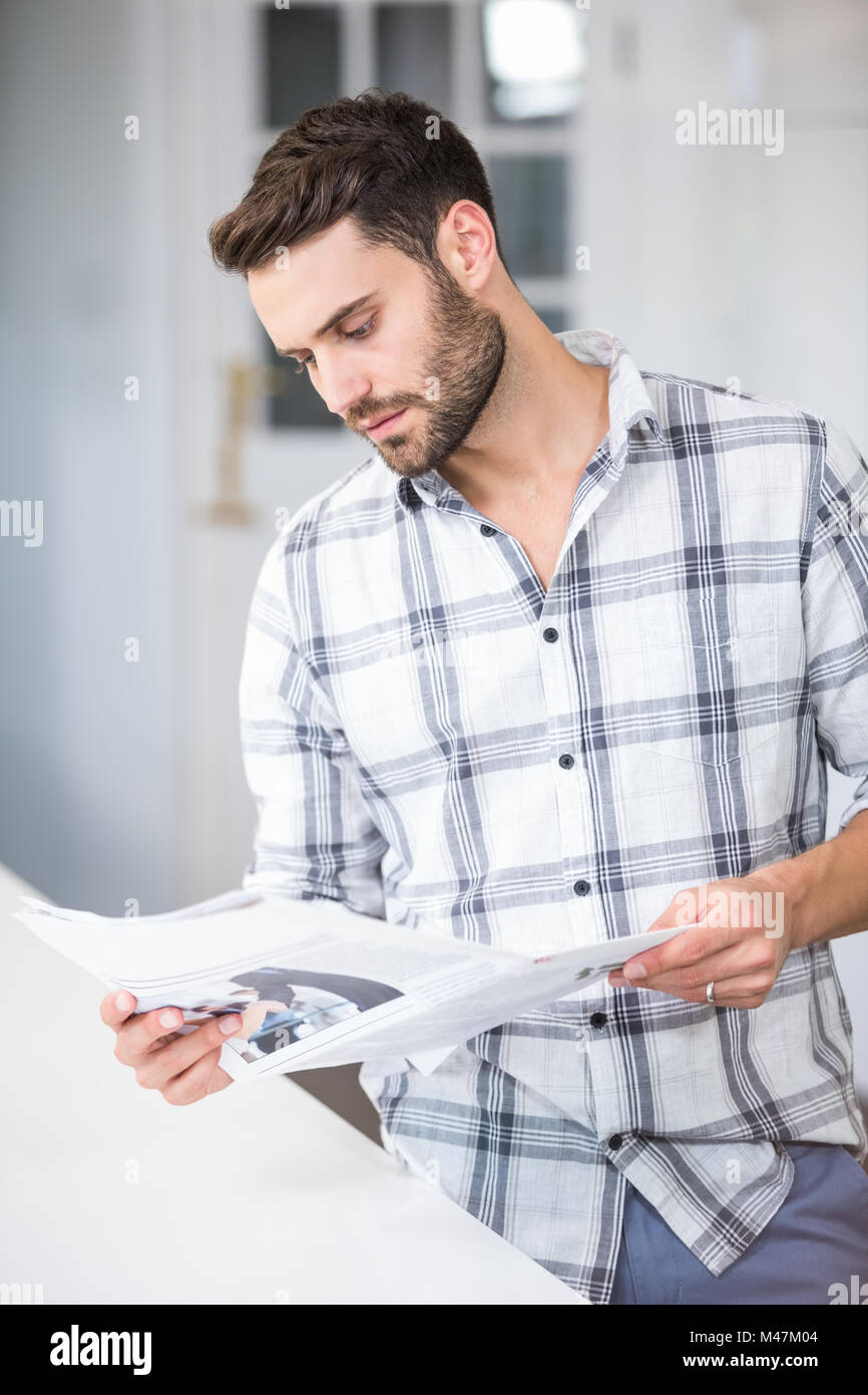 Young man reading documents at table in house Stock Photo - Alamy