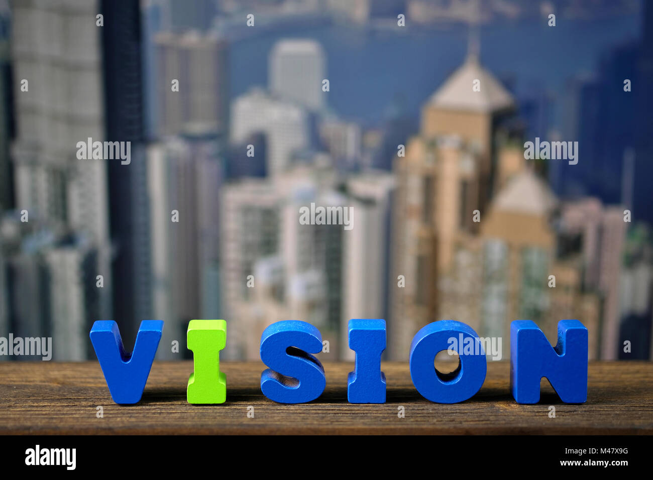 VISION text on top wooden working table with city and office building ...