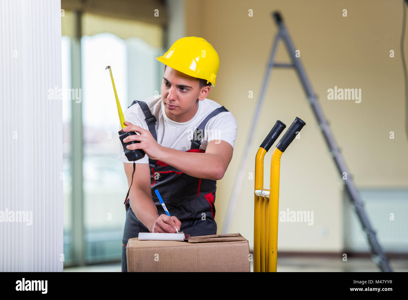Delivery man taking dimensions with tape measure Stock Photo - Alamy