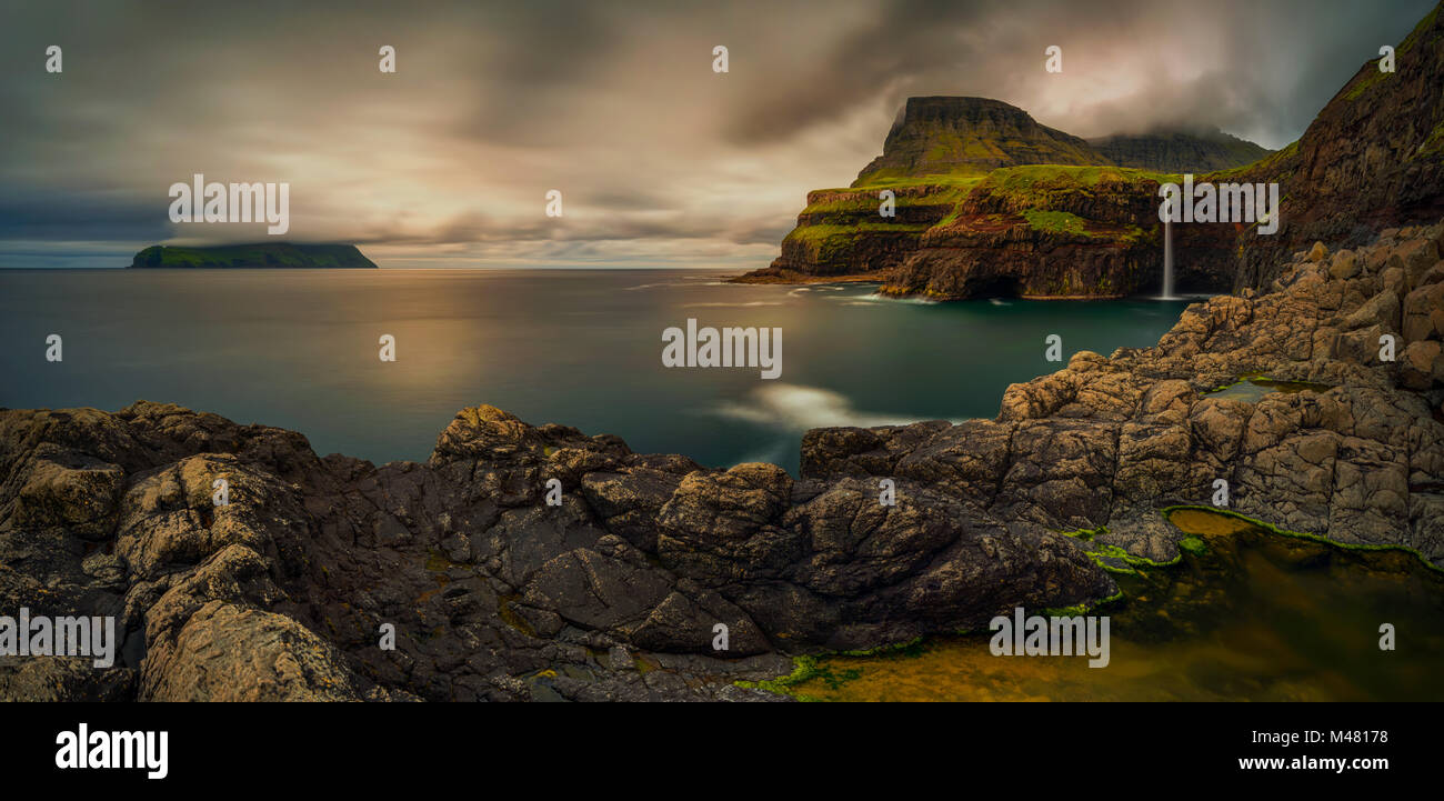 Panorama of Mulafossur waterfall and Mykines in cloudy sunset, Faroe ...