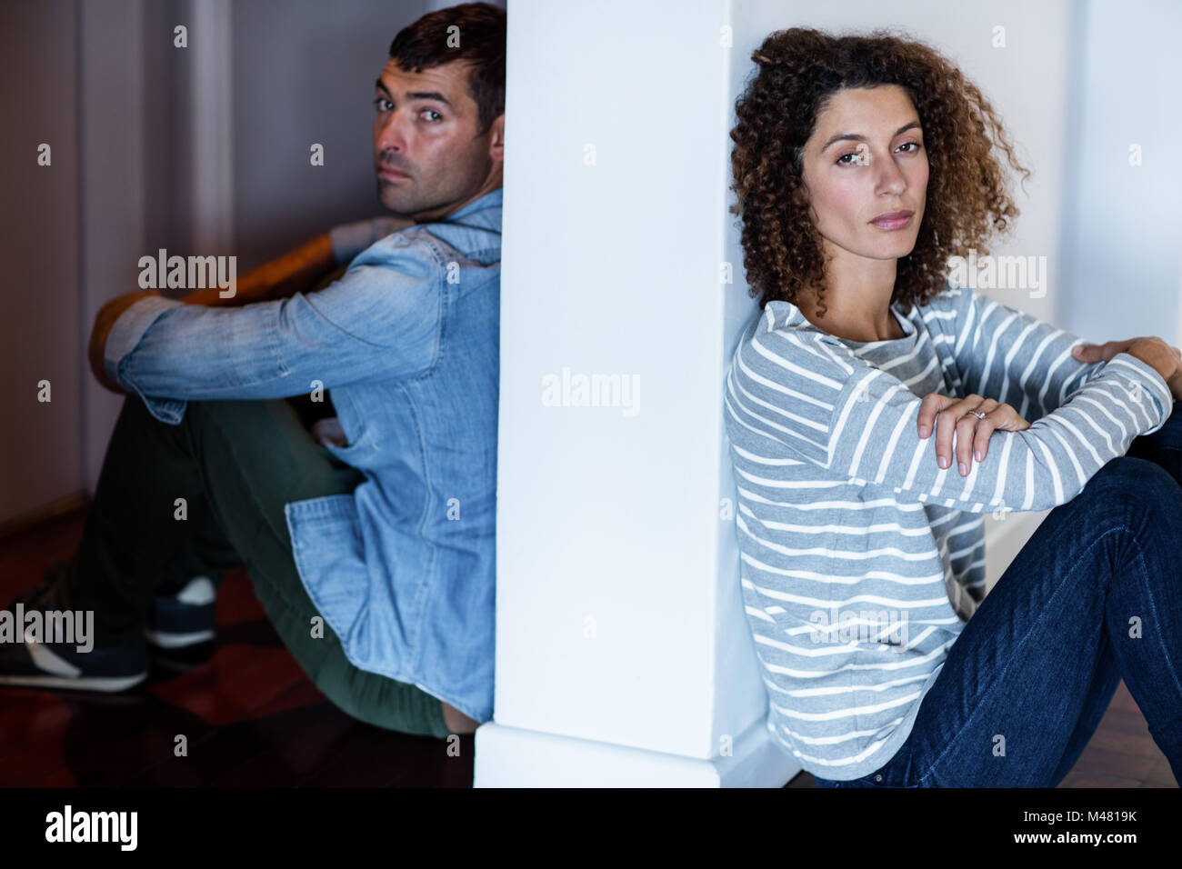 Portrait of couple sitting on opposite sides of the wall Stock Photo ...