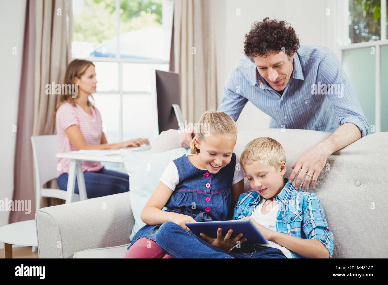 Children using digital tablet while father looking at them Stock Photo ...