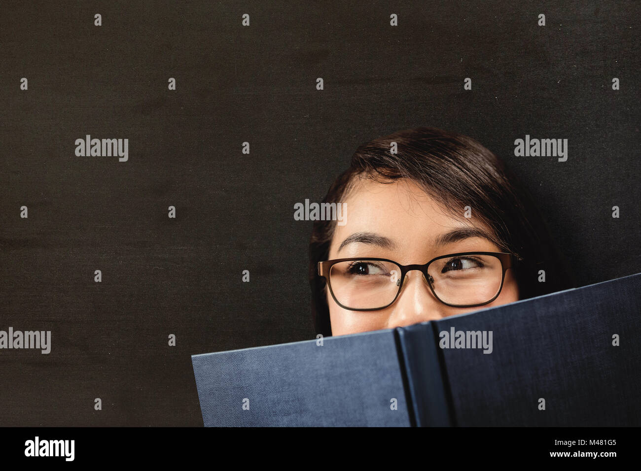 Composite image of pretty student hiding face behind a book Stock Photo ...