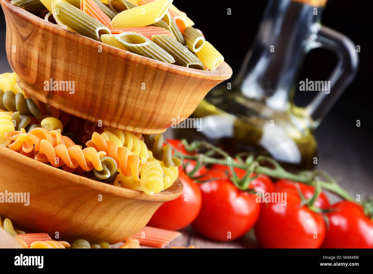 Raw eliche and penne tricolori pasta in the wooden bowls Stock Photo ...