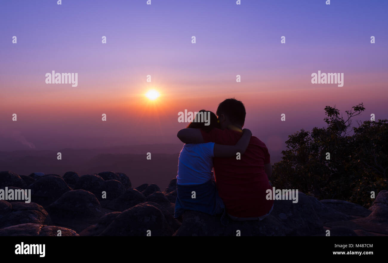 brother and sister sitting on rock and see sunset together at sunset ...