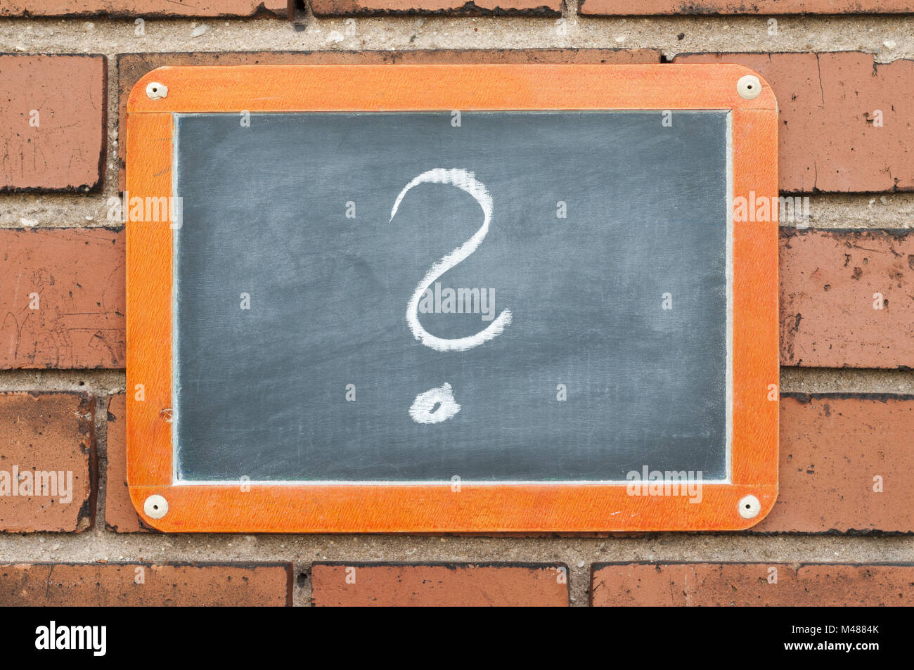 Board on a brick wall with a question mark Stock Photo - Alamy