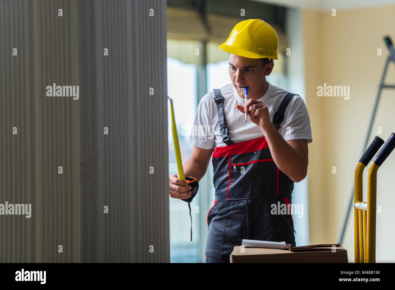Delivery man taking dimensions with tape measure Stock Photo - Alamy