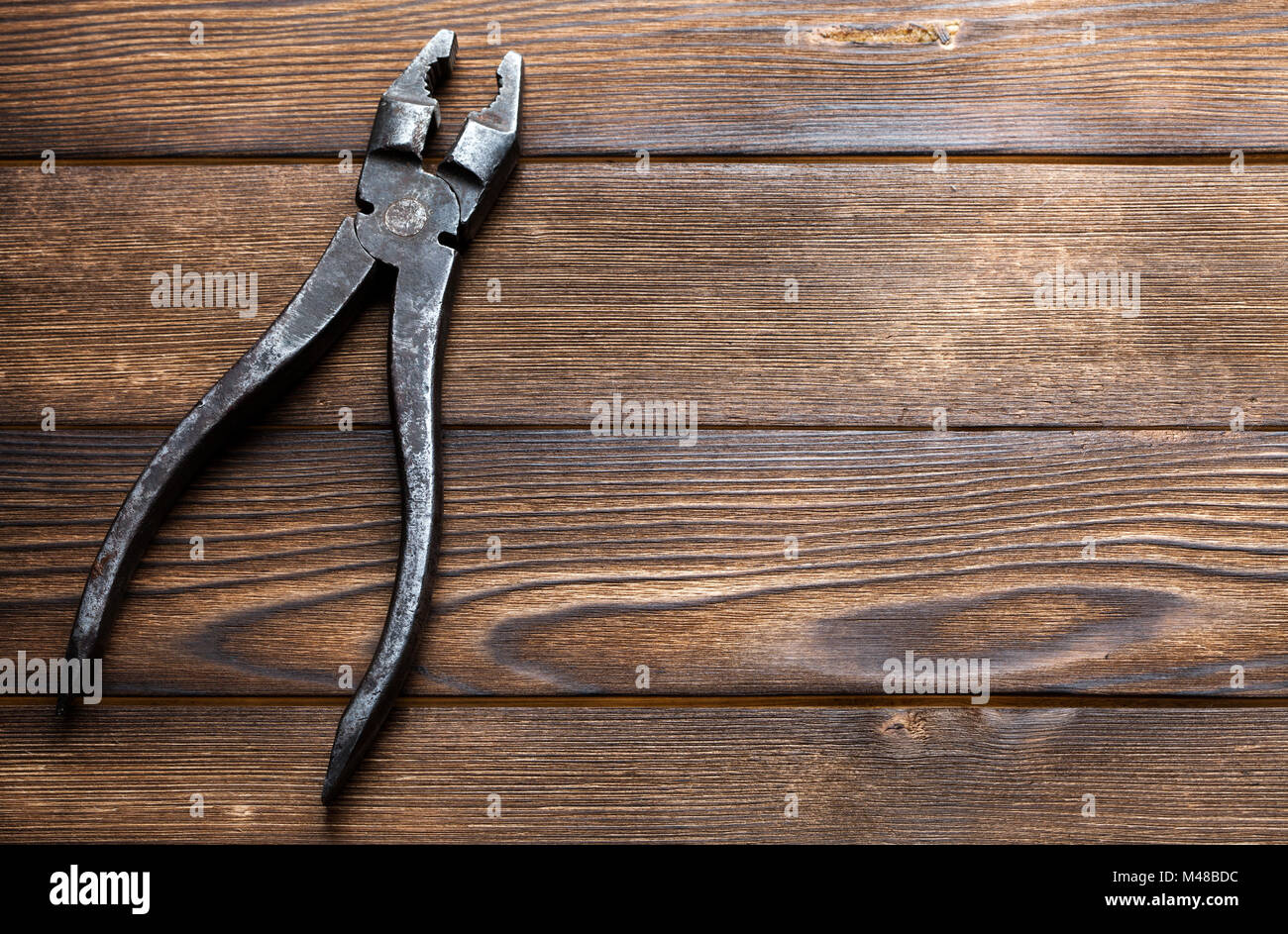 old rusty pliers on wooden background Stock Photo - Alamy