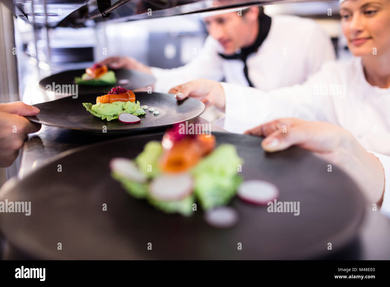 Chef handing appetizer plate through order station Stock Photo - Alamy