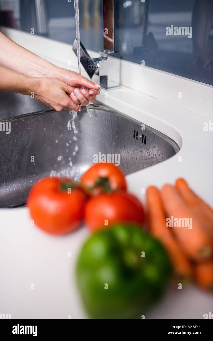 Woman washing hands in sink at kitchen counter Stock Photo - Alamy