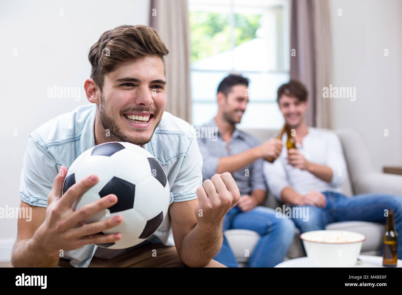 Young man watching soccer match while friends in background Stock Photo ...