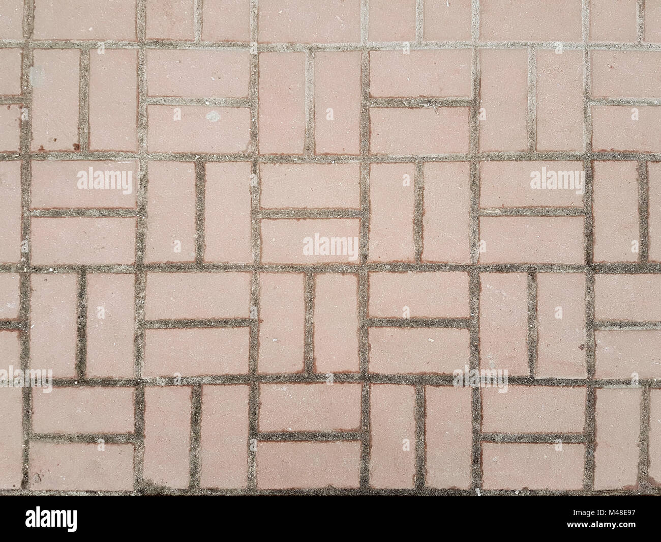 Delicate pink pale square paving tiles, in the seams there is dirt and ...