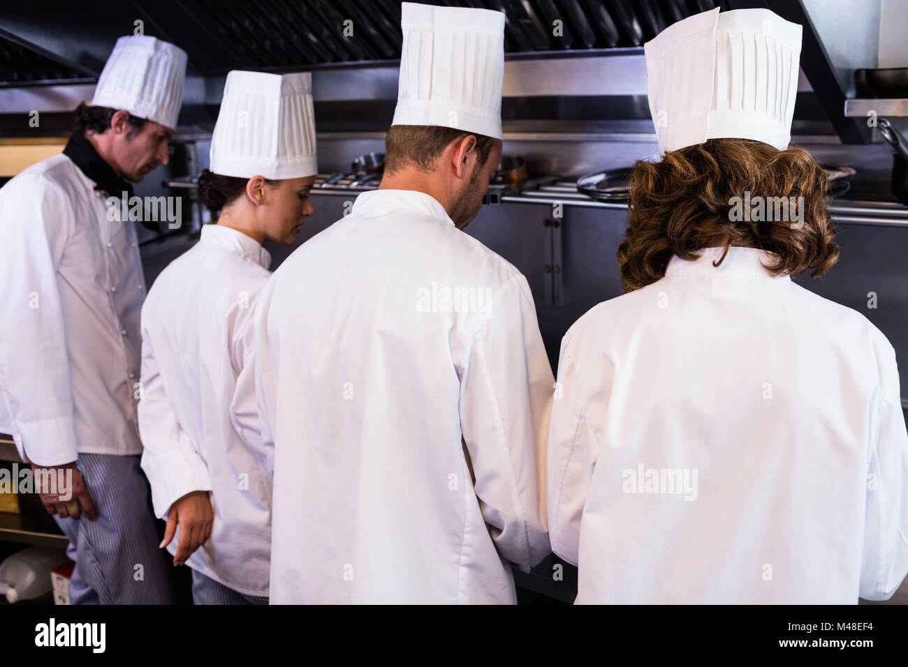 Rear view of chefs preparing food in kitchen Stock Photo - Alamy