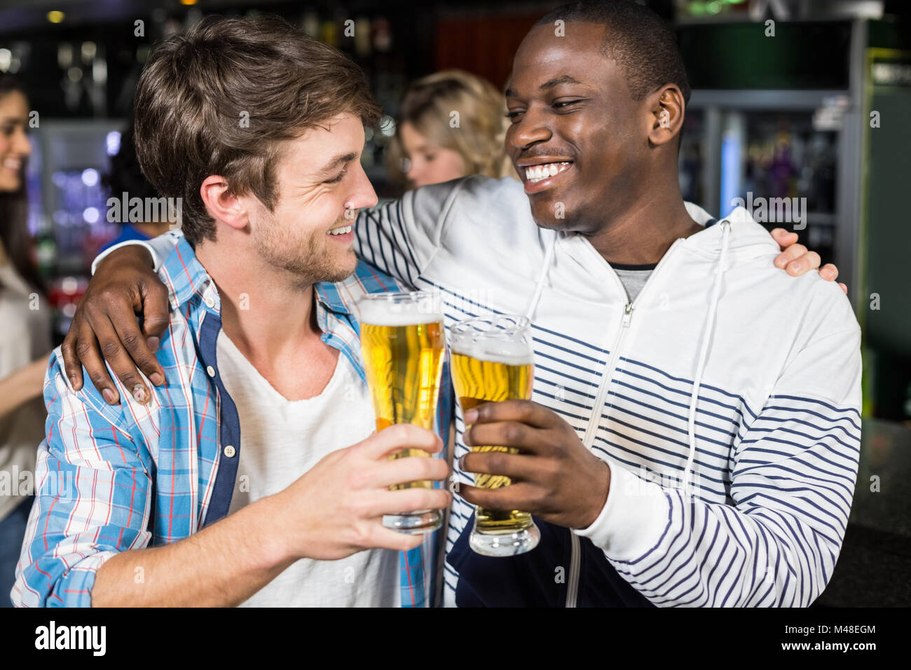 Smiling friends tasting with beer with their friends Stock Photo - Alamy