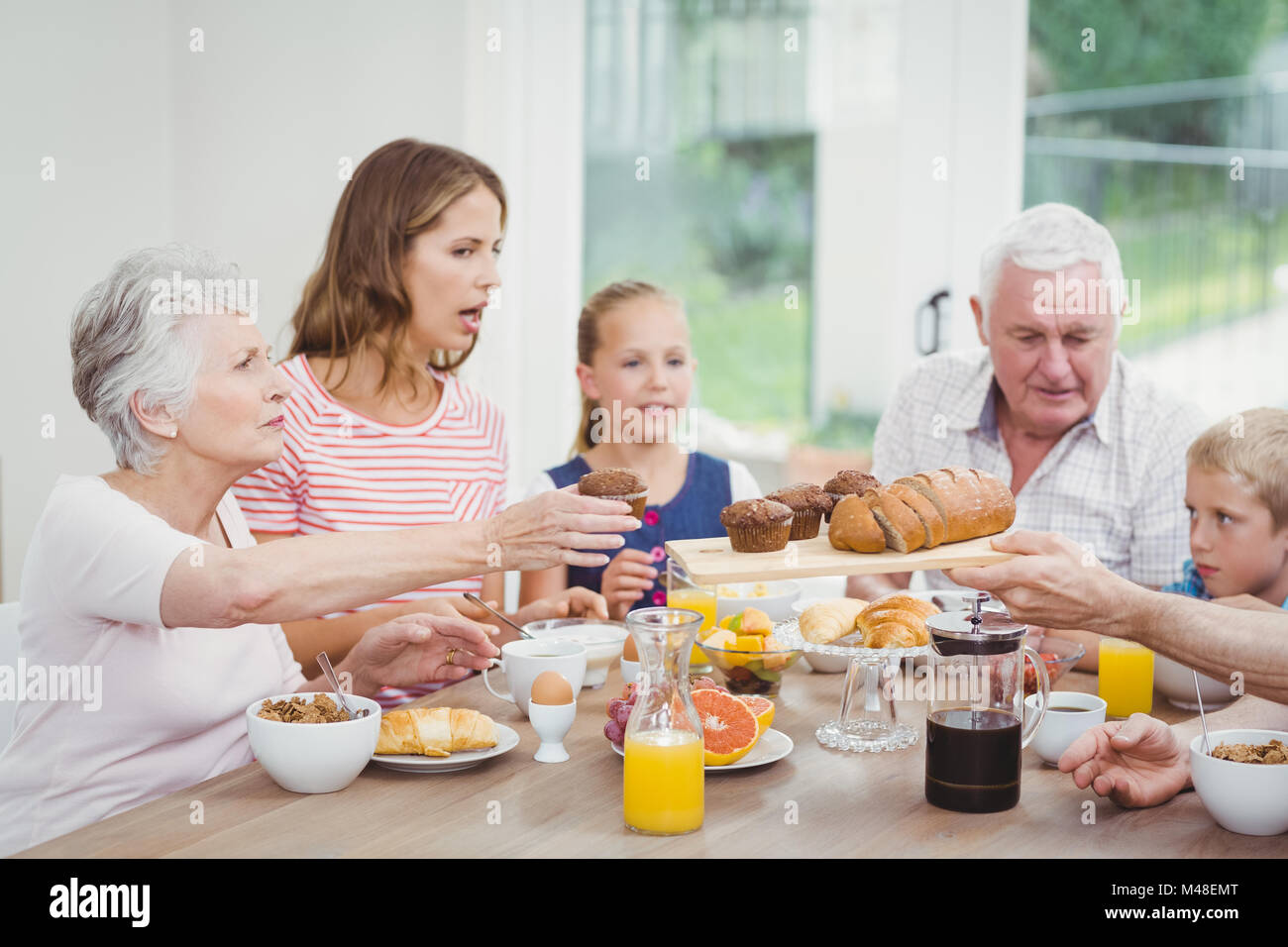 Multi-generation family having muffins during breakfast Stock Photo - Alamy
