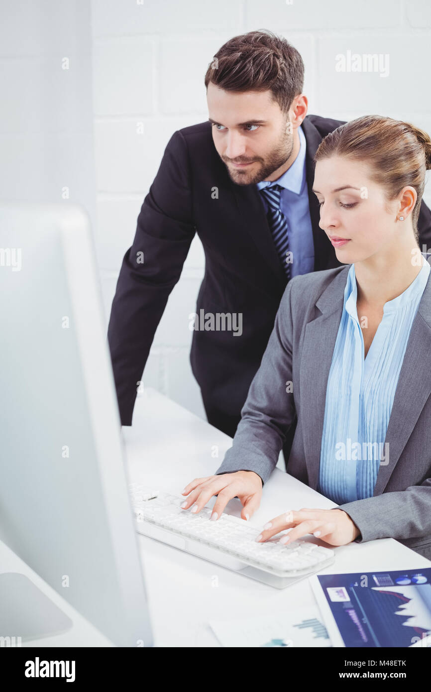 Businessman looking in computer monitor while colleague typing Stock ...