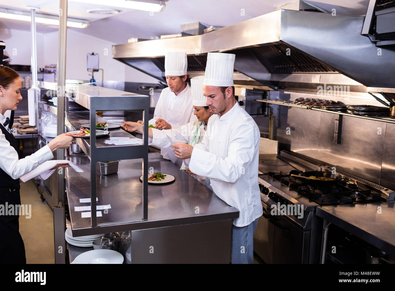 Group of chef preparing food in commercial kitchen Stock Photo - Alamy