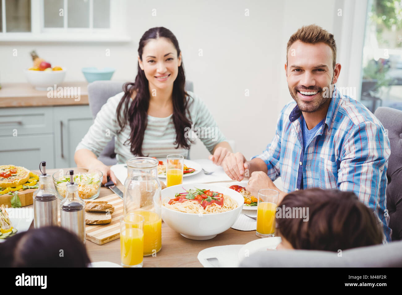 Smiling parents with children sitting at dining table Stock Photo - Alamy