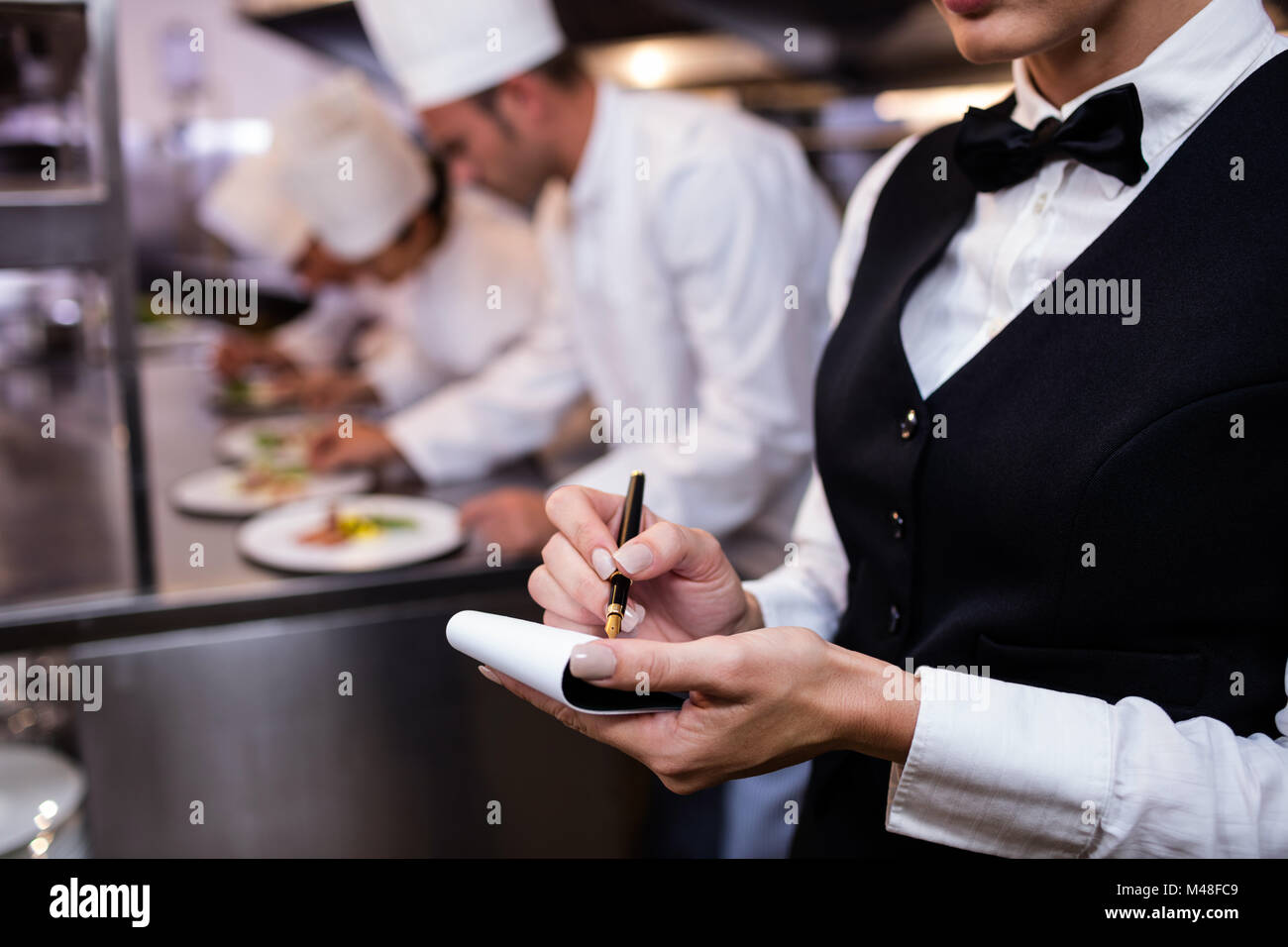 Close-up of waitress with note pad in commercial kitchen Stock Photo ...